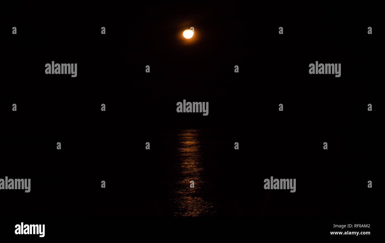 moonlight reflections on sea. Full moon setting on horizon in ocean ...
