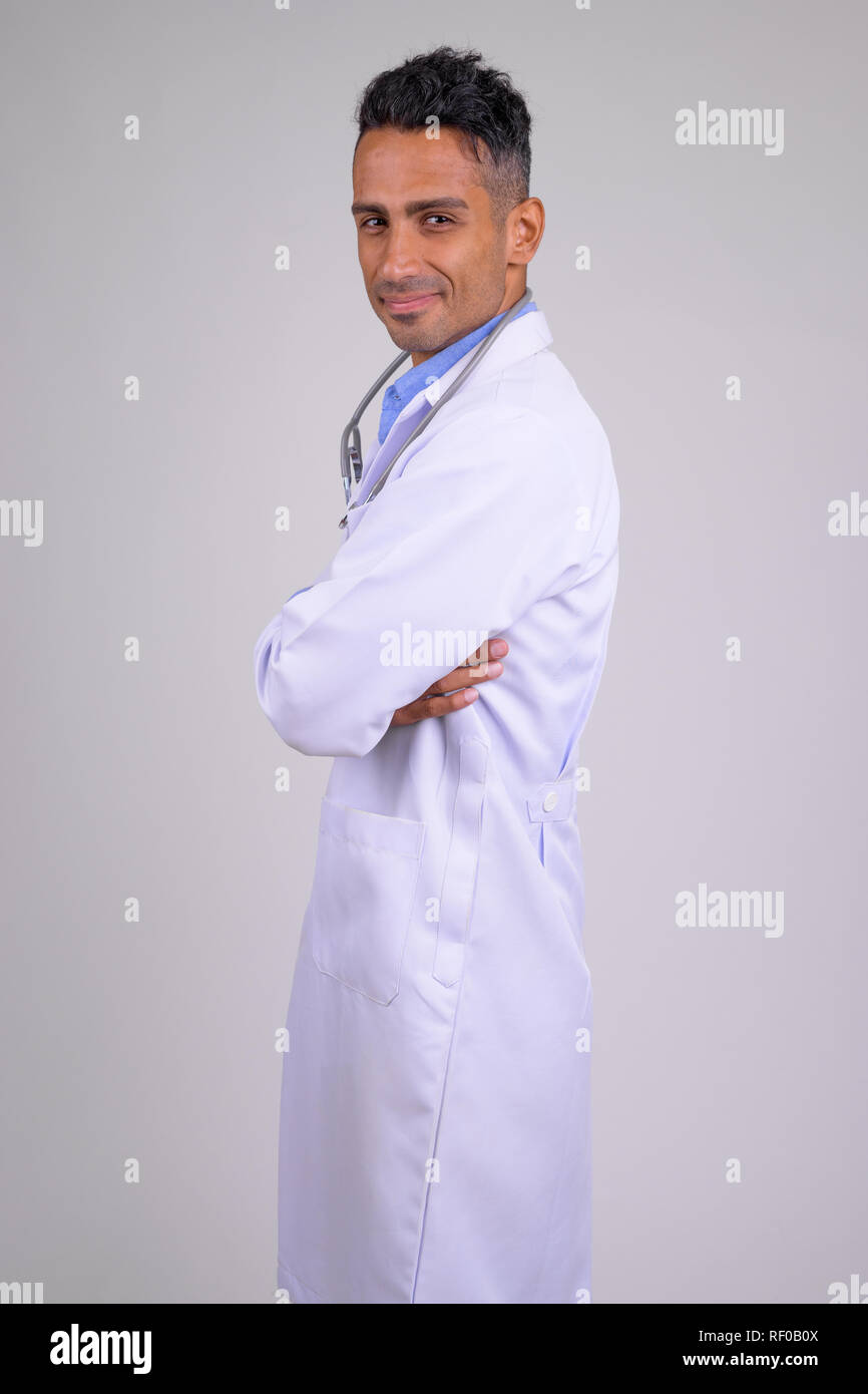 Profile view of young happy Persian man doctor smiling with arms ...