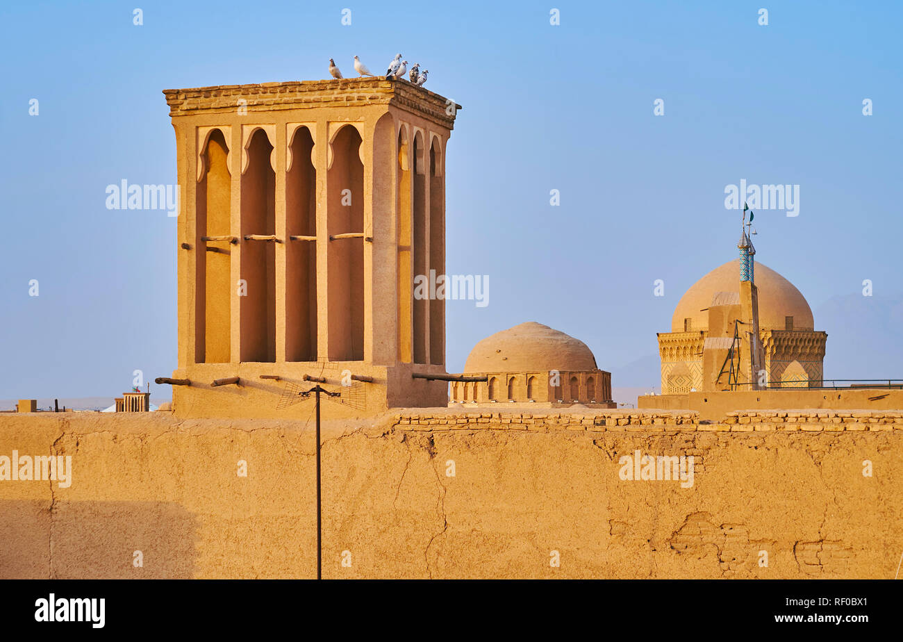 The small flock of white pigeons sits on the medieval adobe badgir ...