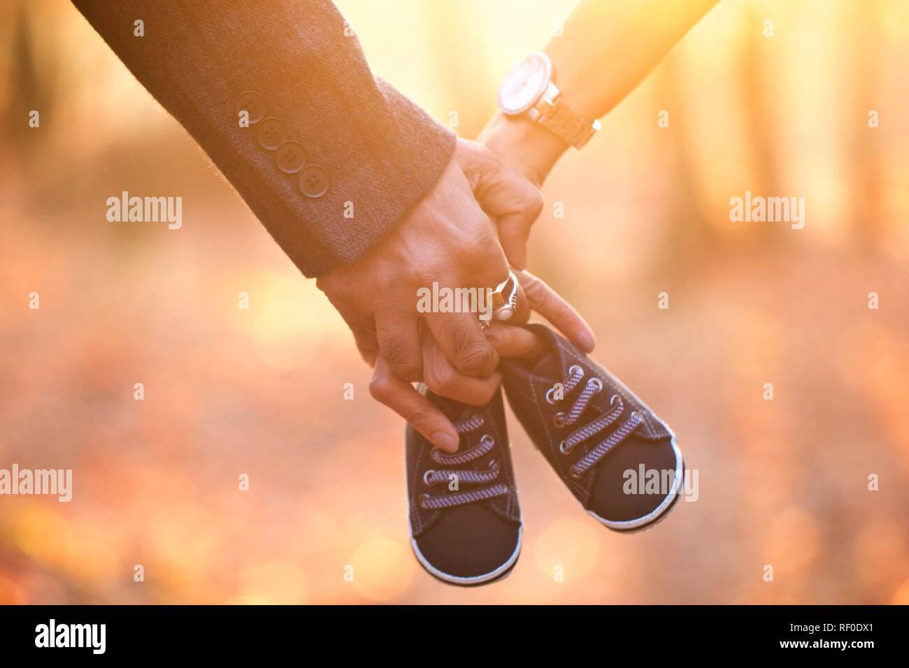 Couple holding hands and child's shoes Stock Photo - Alamy