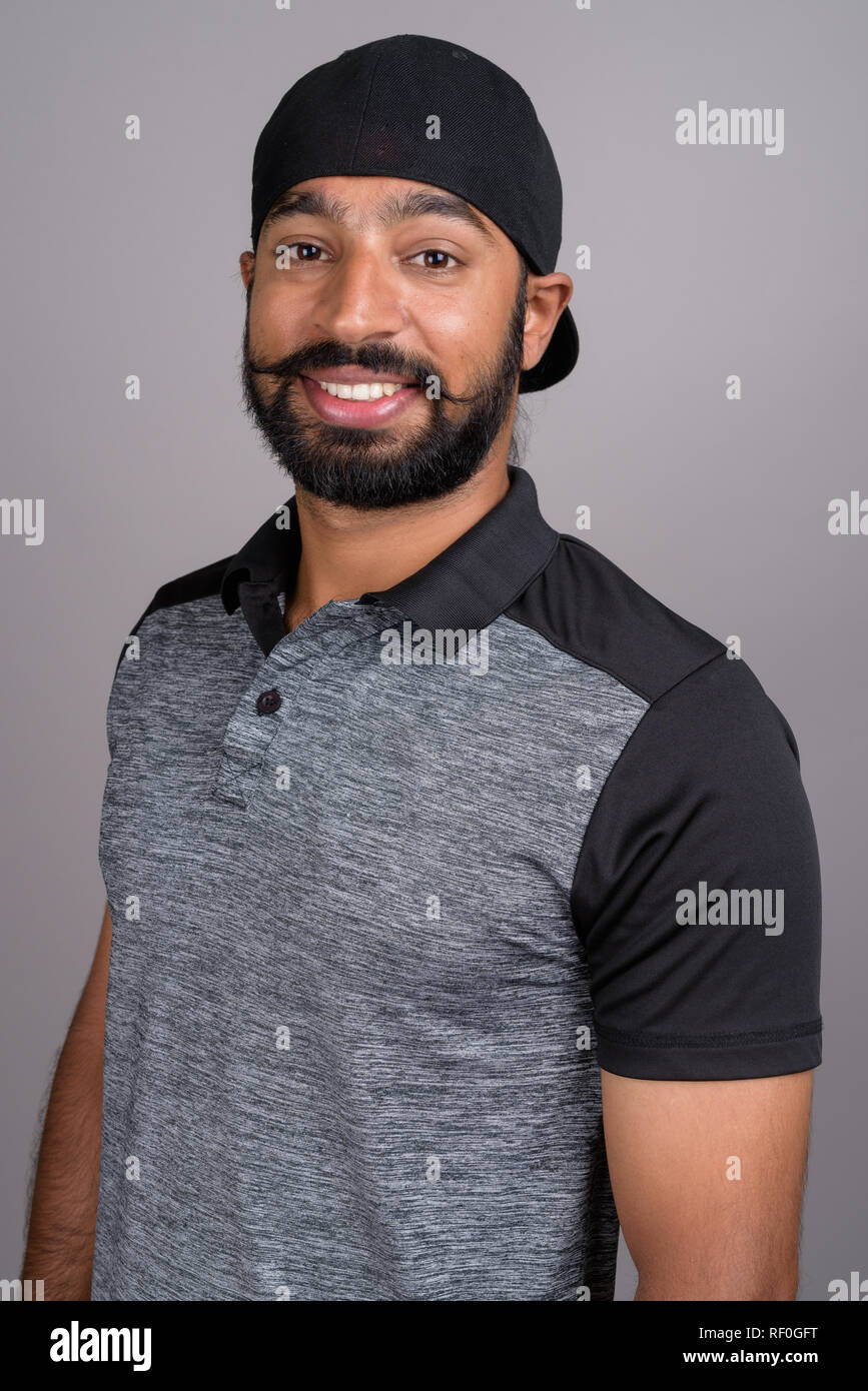 Young handsome Indian man smiling against gray background Stock Photo ...