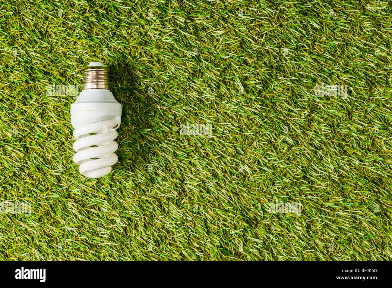 top view of fluorescent lamp on green grass, energy efficiency concept ...