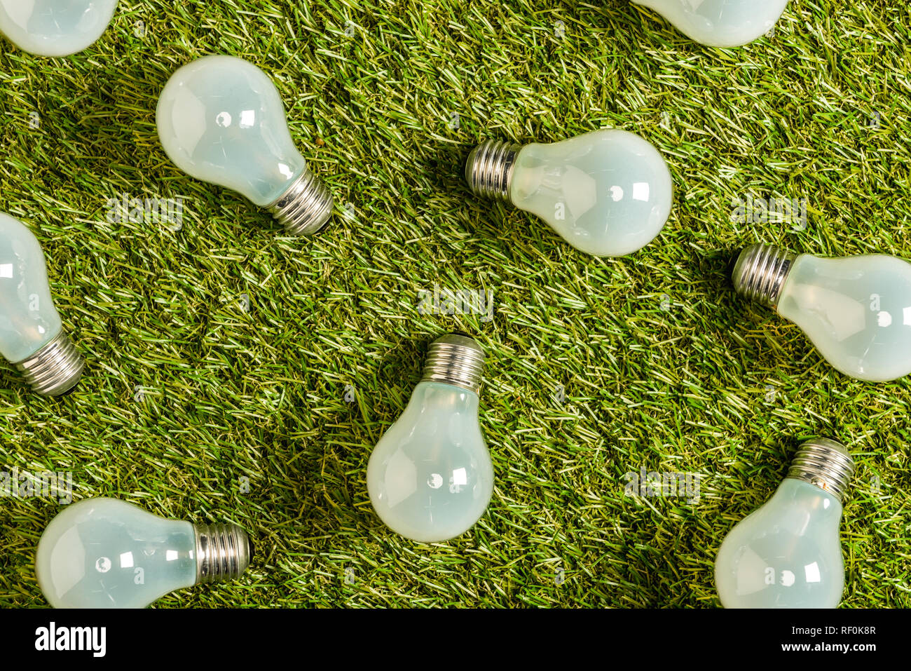 top view of modern fluorescent lamps on green grass, energy efficiency ...