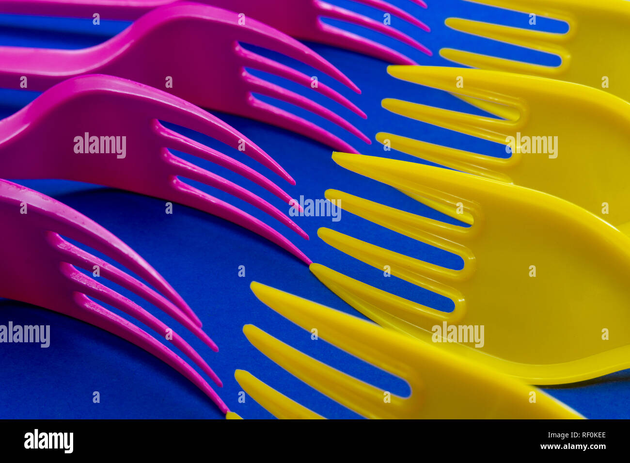 Colorful purple and yellow plastic forks arranged in a diagonal line on ...