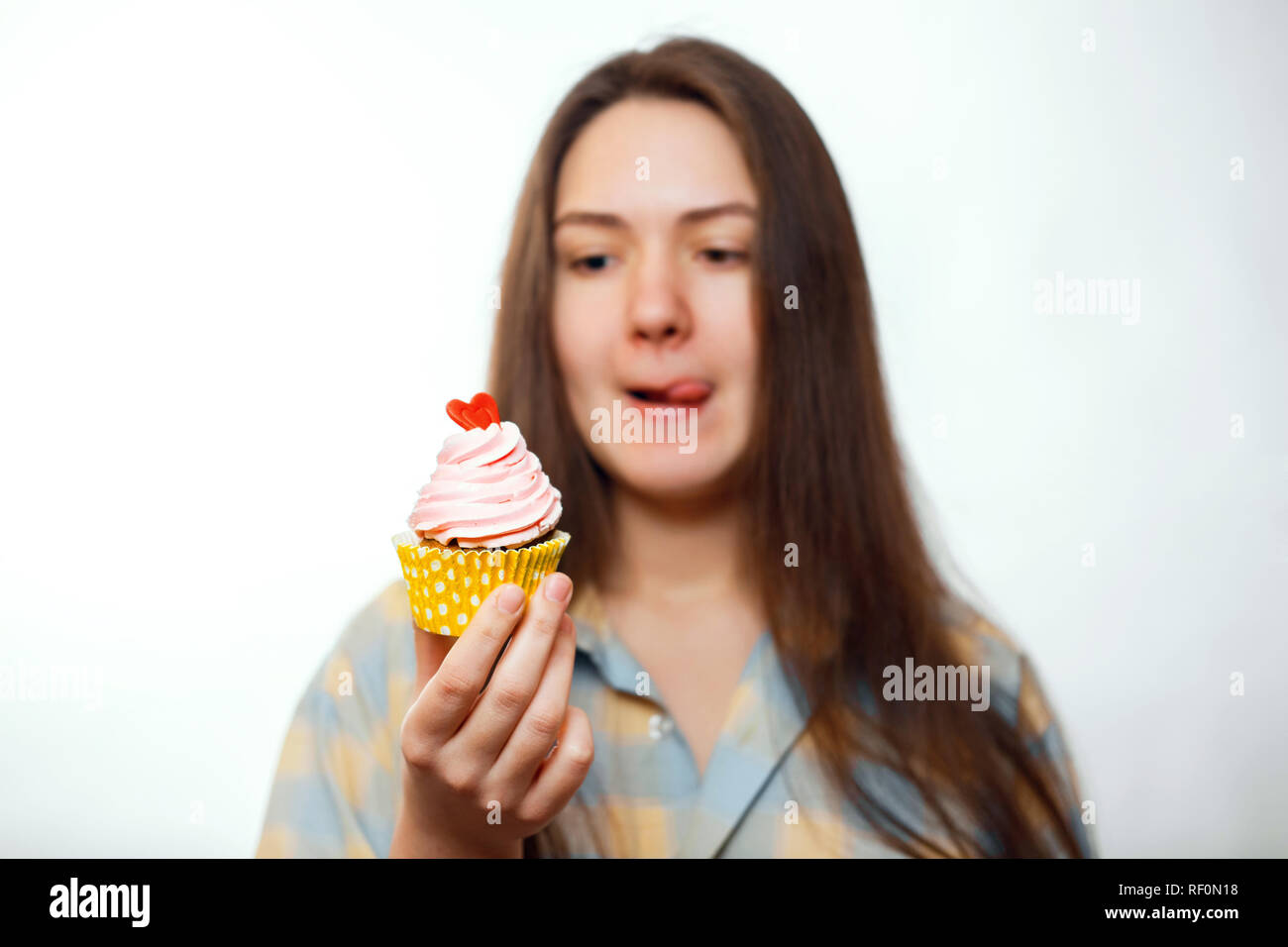 funny young woman licked and wants to eat pink cake Stock Photo - Alamy