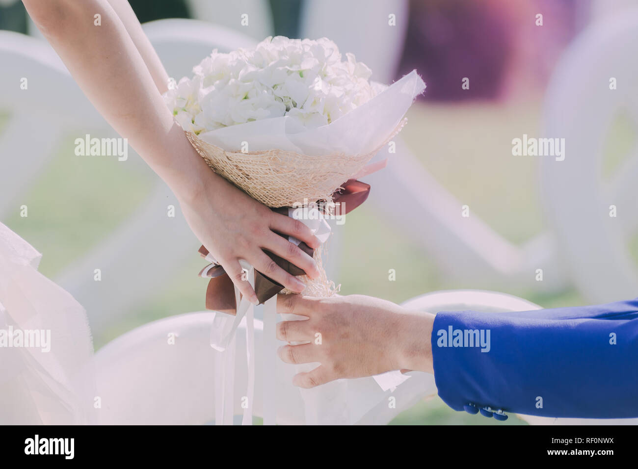 The bride and groom join hands and hold a beautiful bouquet on wedding ...