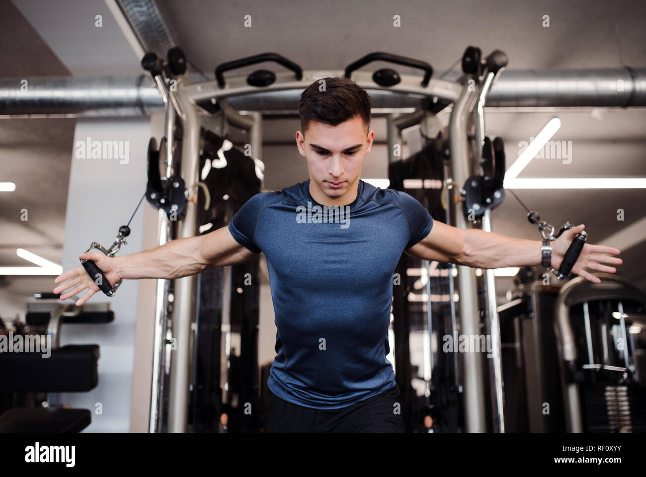 A concentrated young handsome man doing strength workout exercise in ...