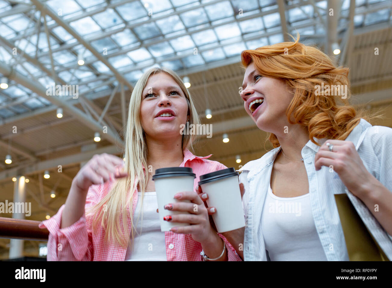 Two beautiful smiling women with disposable coffee cups talking in ...