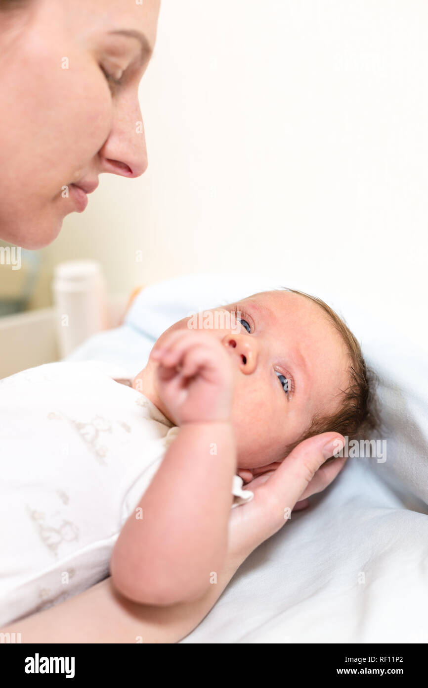 Young mother hugging her newborn child. Mom nursing baby. Family at ...