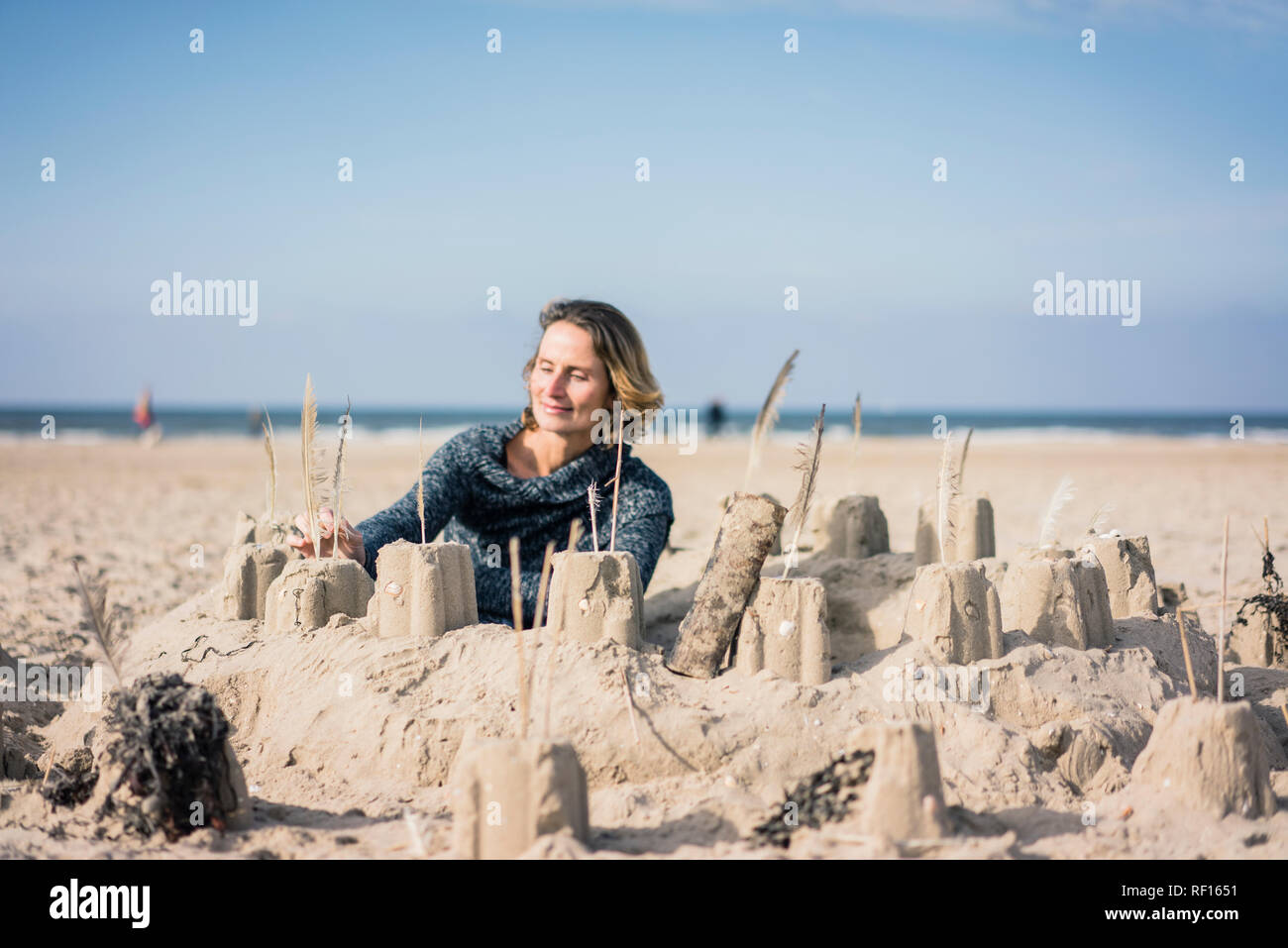 Mature woman building a sandcastle on the beach Stock Photo - Alamy