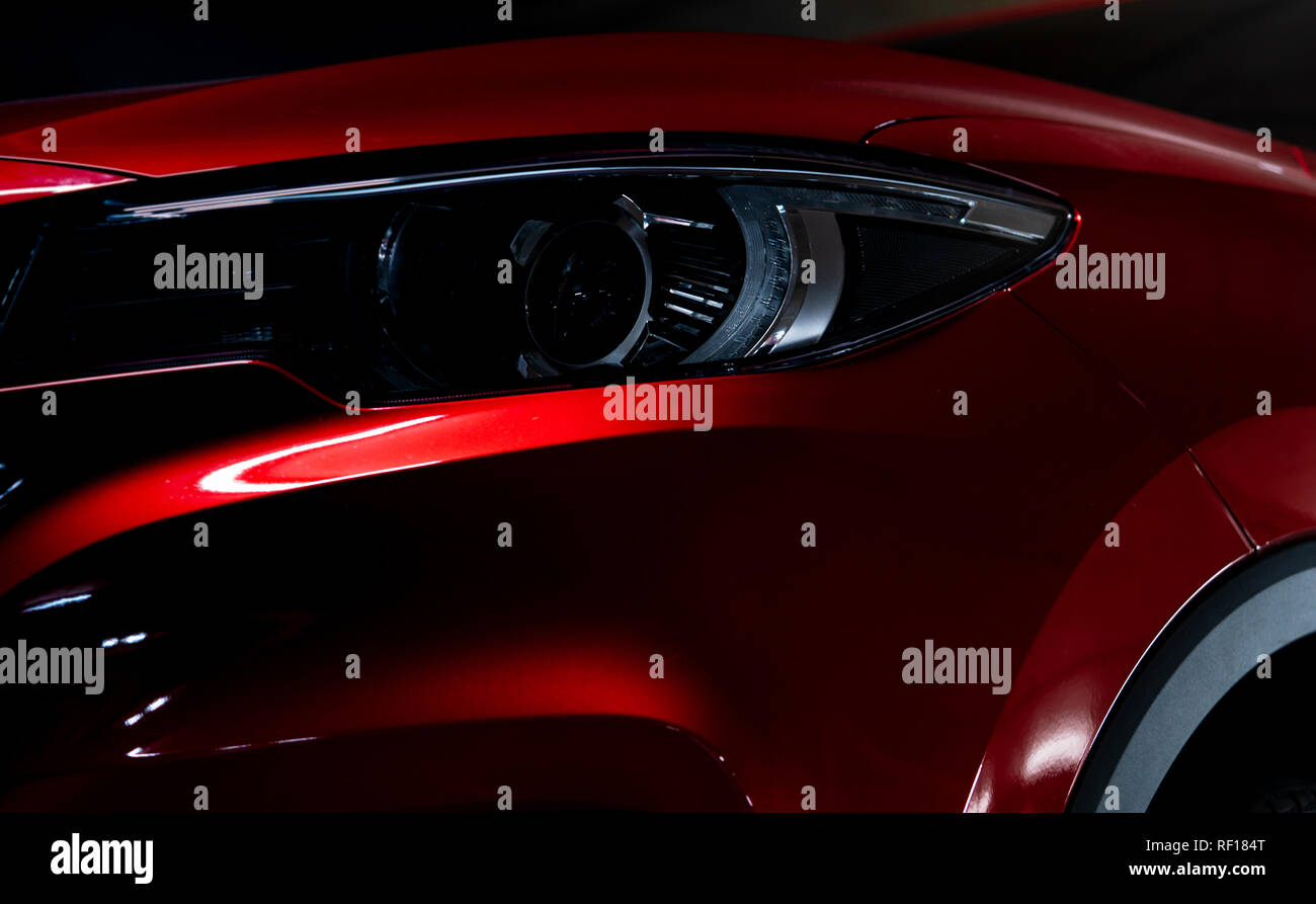 Closeup headlight of shiny red luxury SUV compact car. Elegant electric ...