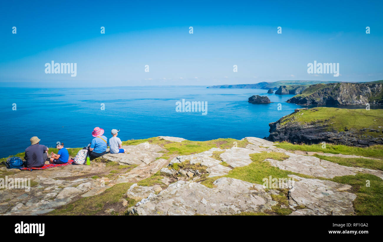 People are sitting on the rocks of Tintagel Island with ocean, cliffs ...