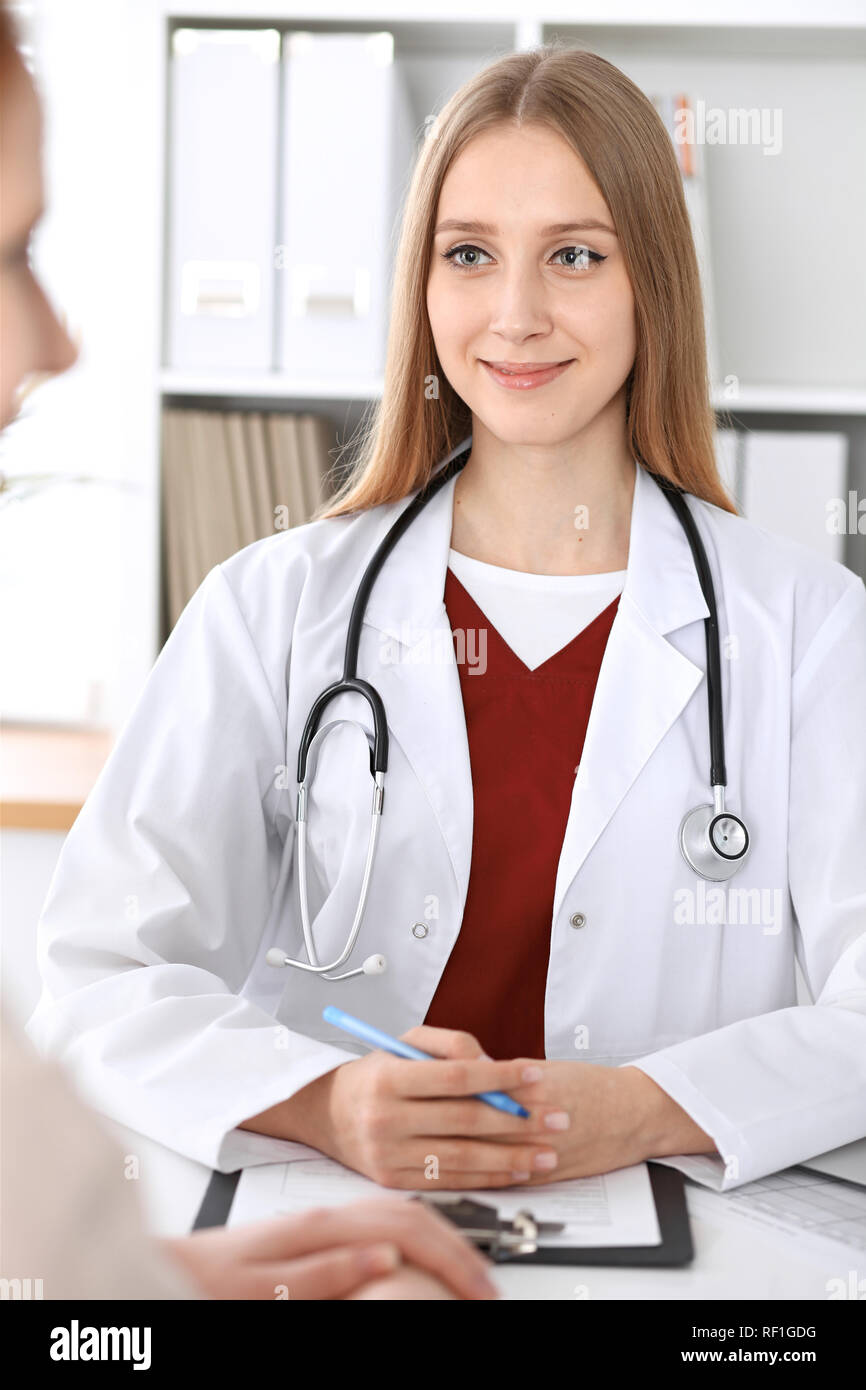 Close-up of a female doctor filling up an application form while ...