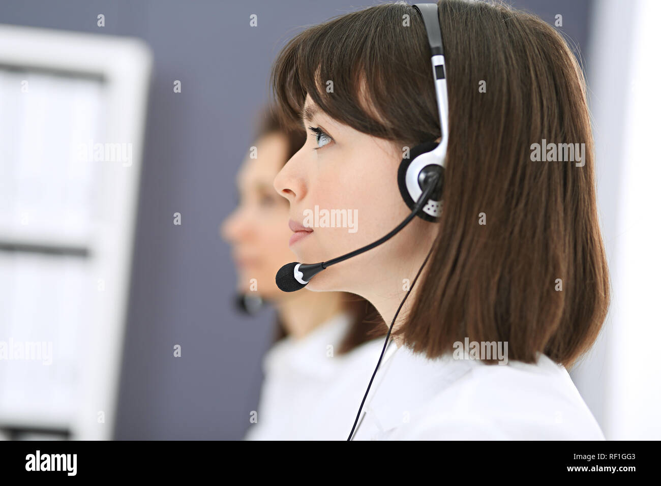 Call center. Group of operators at work. Focus on young brunette woman. Business concept Stock ...
