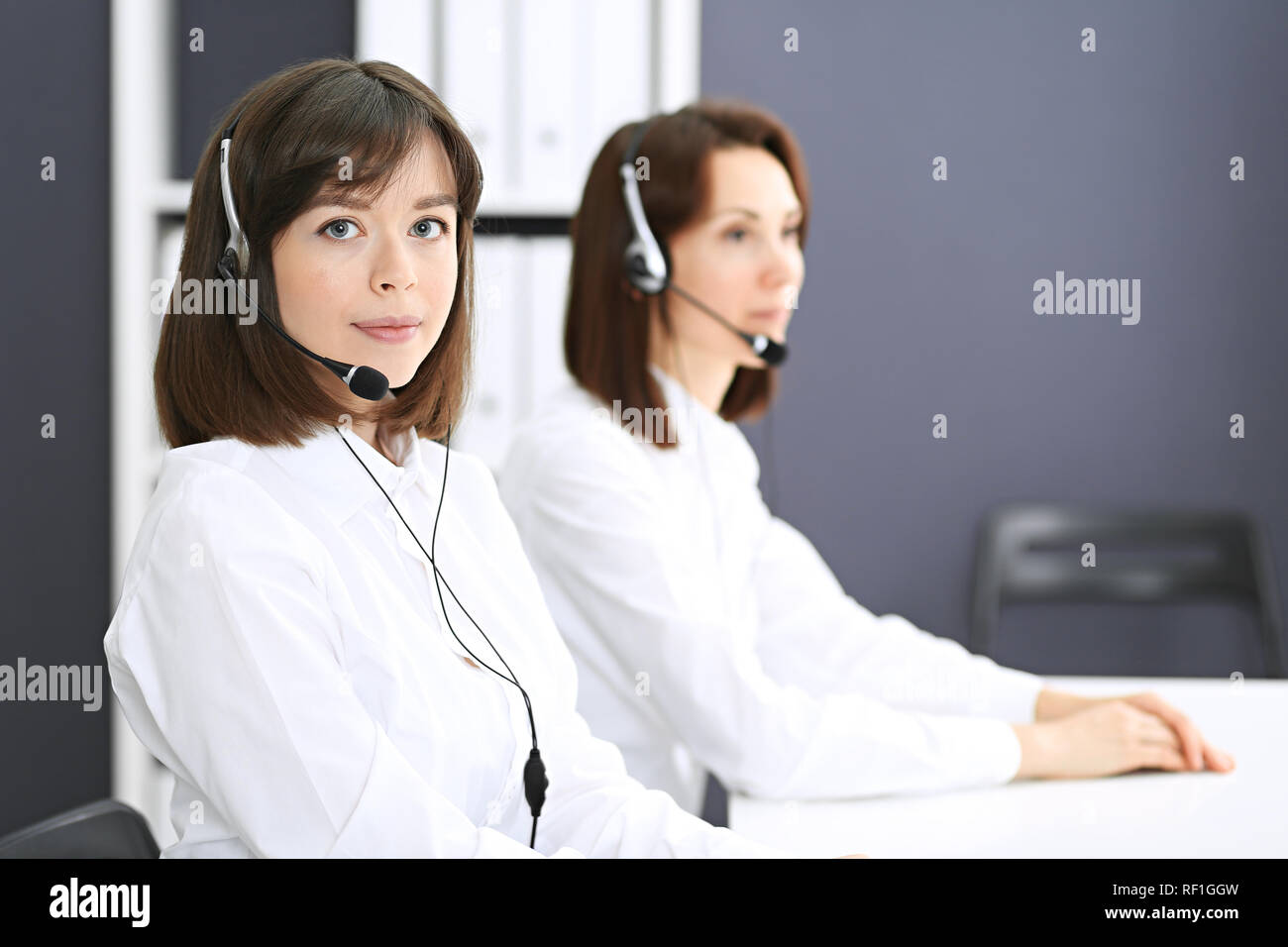 Call center. Group of operators at work. Focus on young brunette woman. Business concept Stock ...