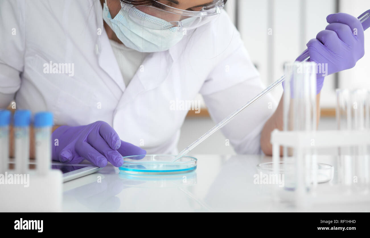 Close-up of professional female scientist in protective eyeglasses ...