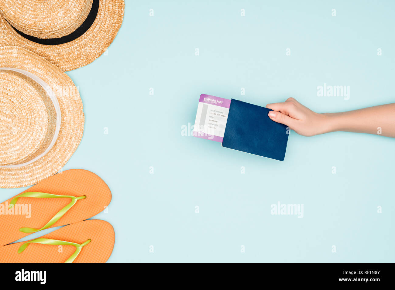 cropped view of woman holding air ticket and passport near flip flops ...