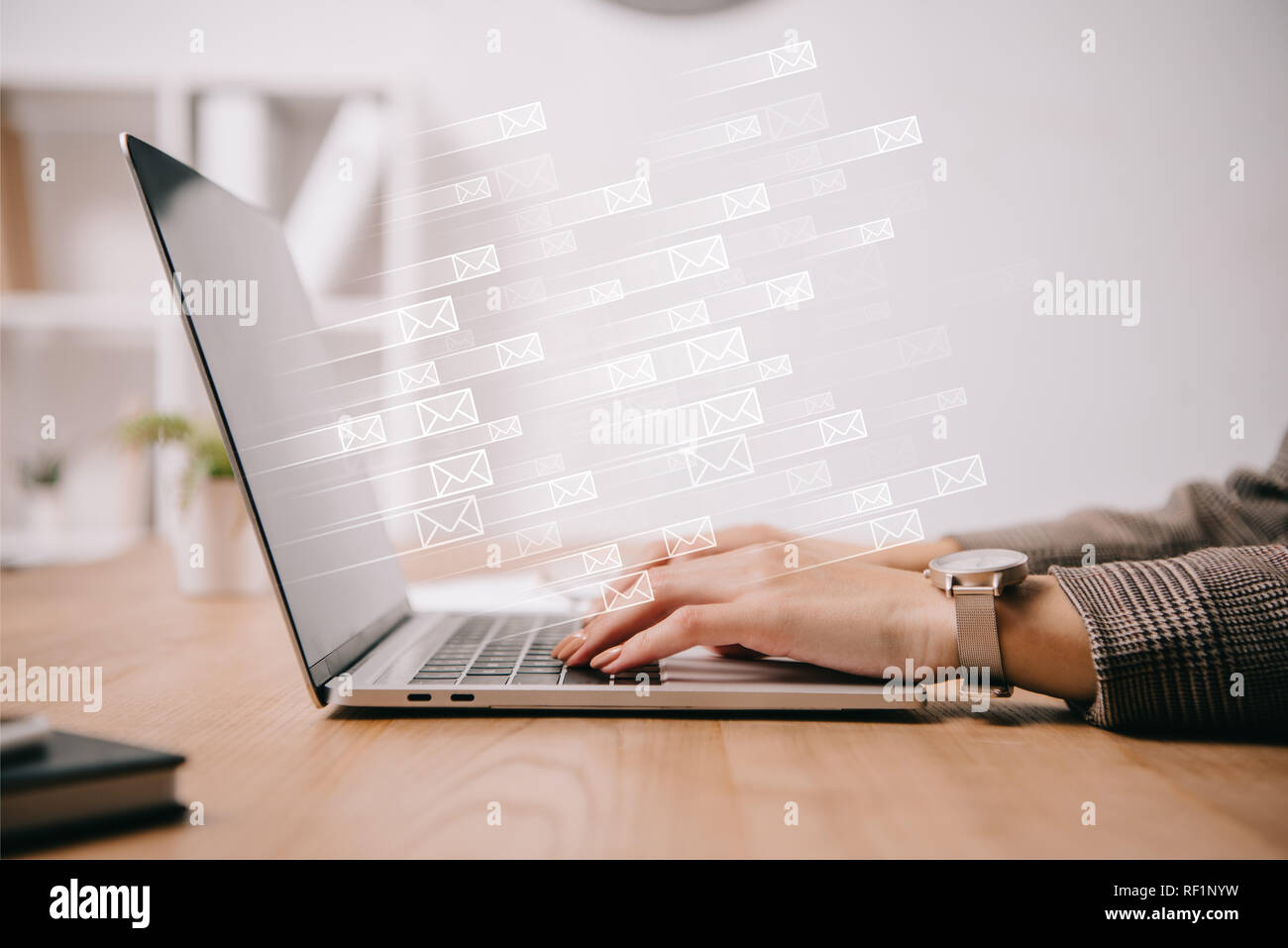 cropped view of businesswoman working and typing on laptop with sending ...