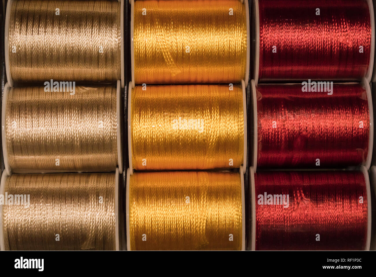 Cutout texture closeup on coils of colored sewing threads gold, yellow ...