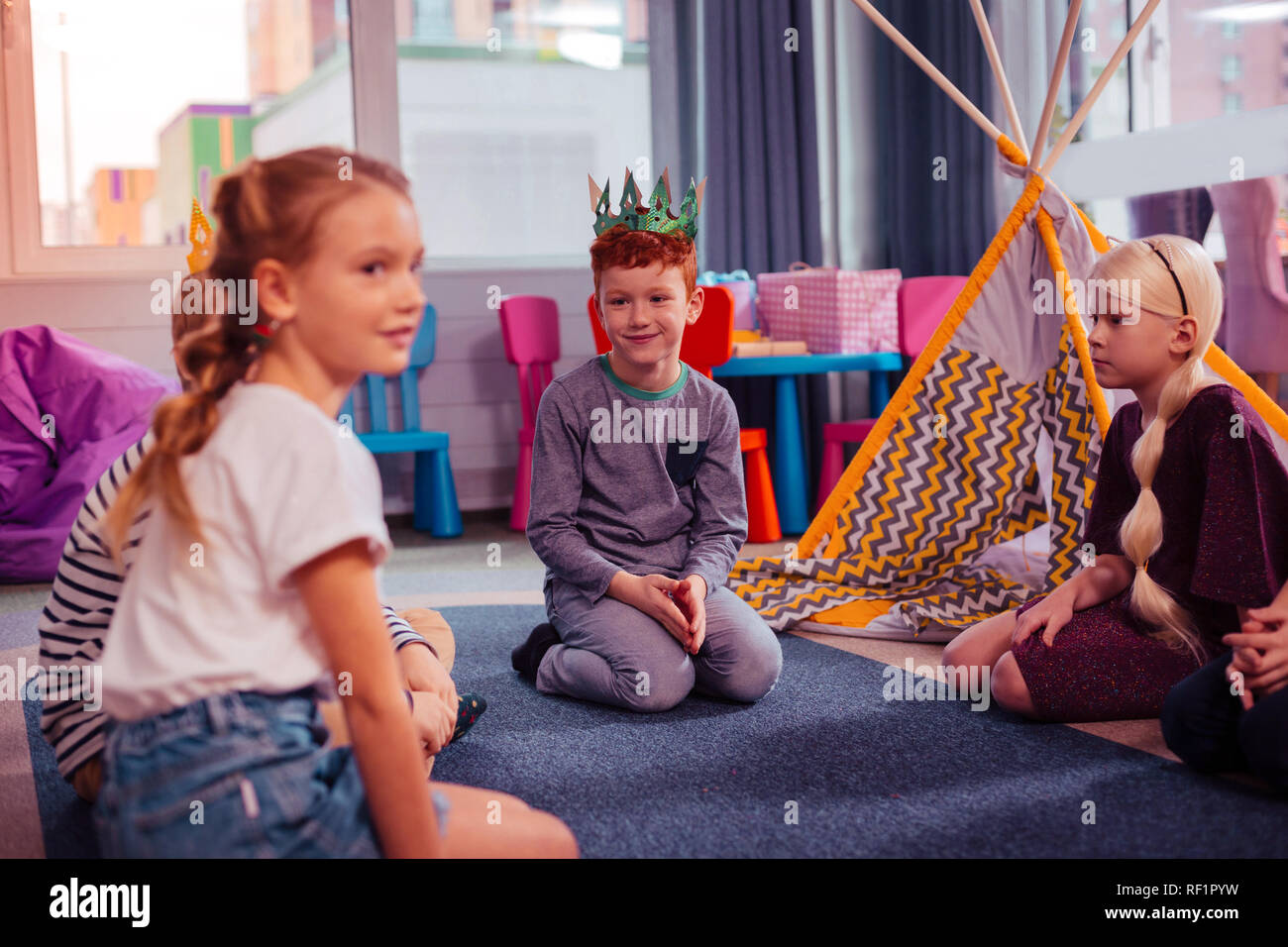 Pleased boy wearing paper crown during playing Stock Photo - Alamy