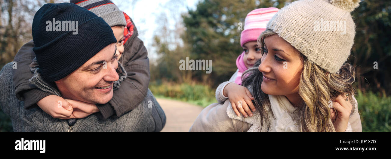 Parents giving piggyback ride to happy children outdoors Stock Photo ...