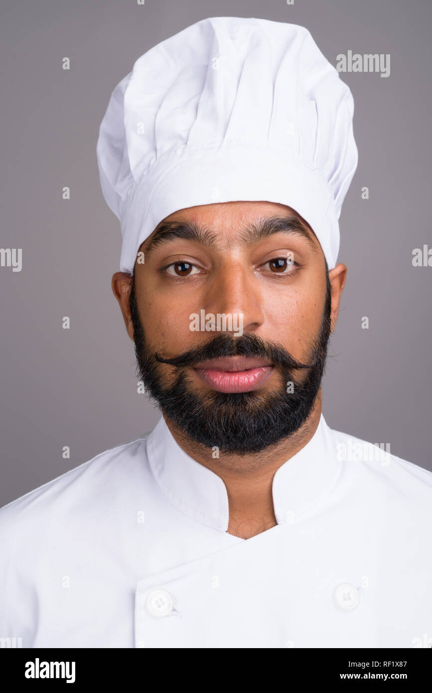 Young handsome Indian man chef against gray background Stock Photo - Alamy