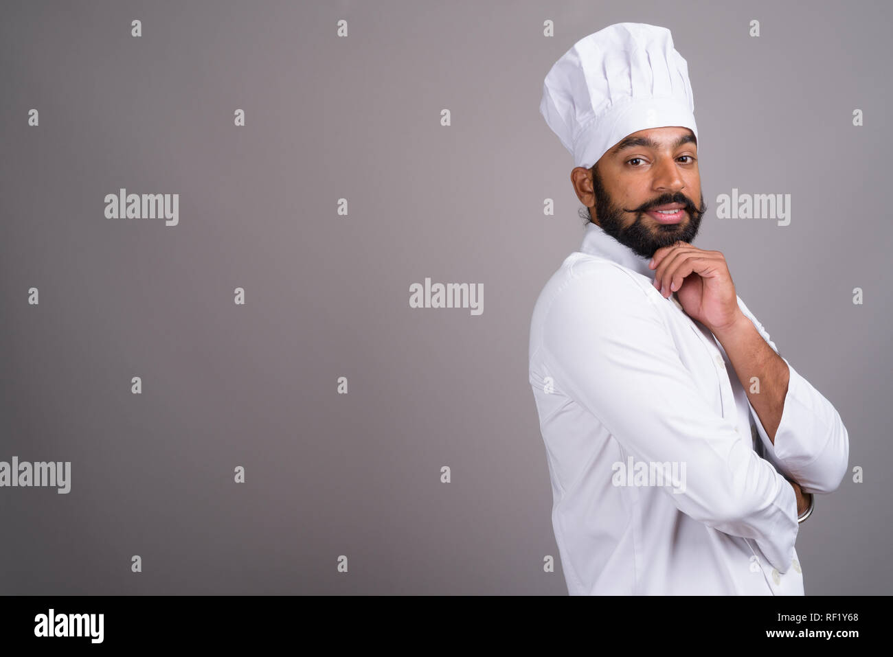 Young handsome Indian man chef against gray background Stock Photo - Alamy