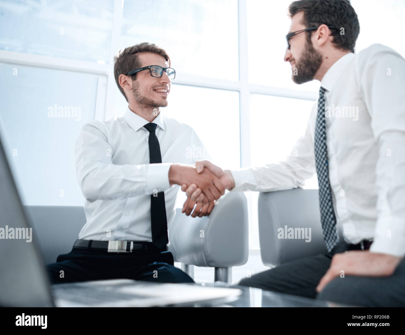 business people shake hands sitting in the hall of the business center ...