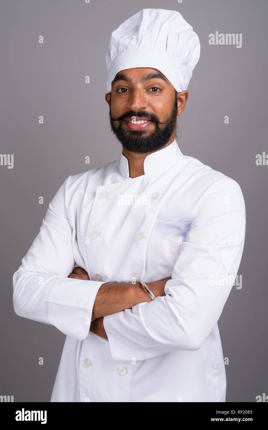 Portrait of young handsome Indian man chef smiling Stock Photo - Alamy