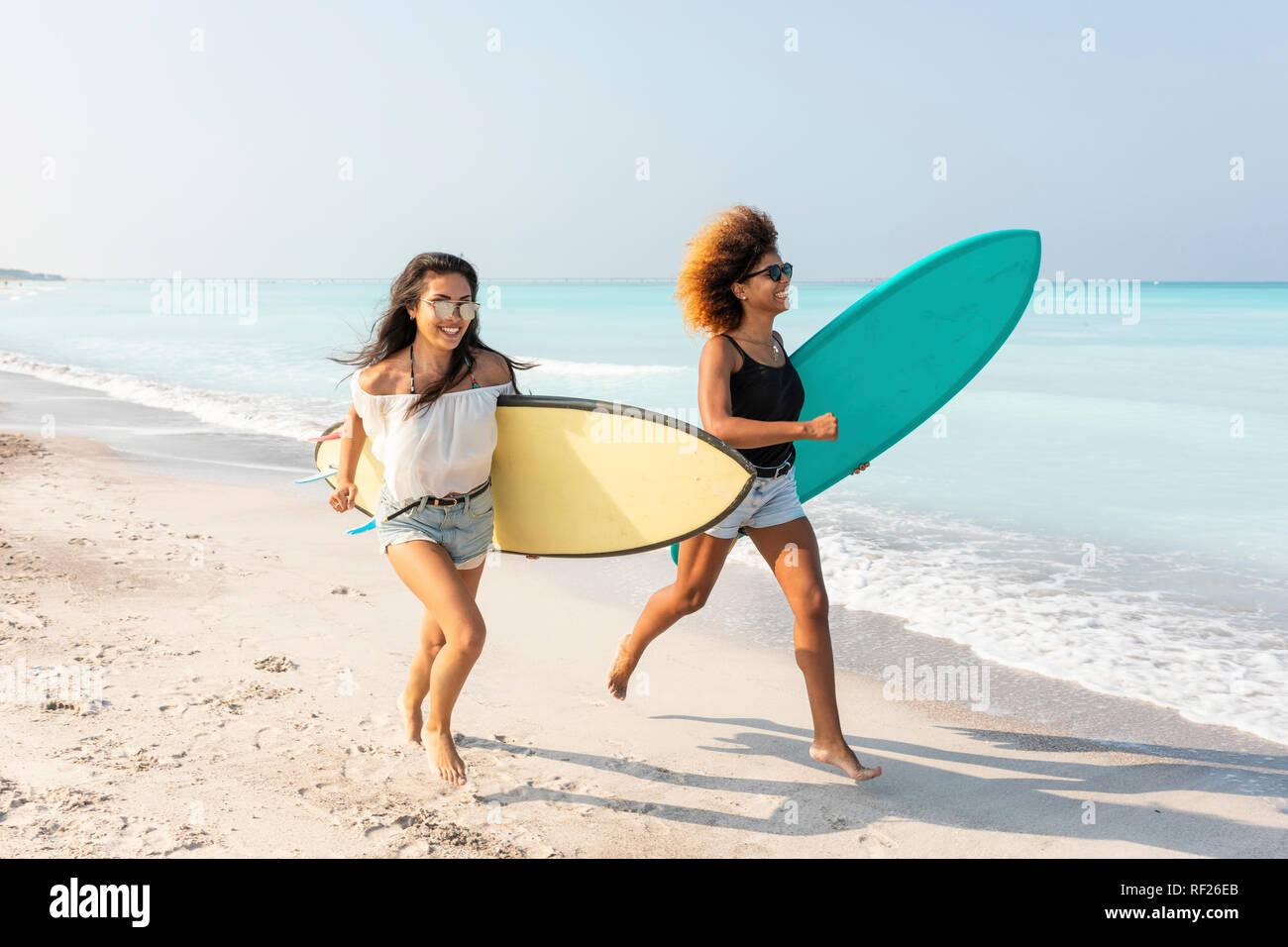 Girl friends running on the beach, carrying surfboards Stock Photo - Alamy