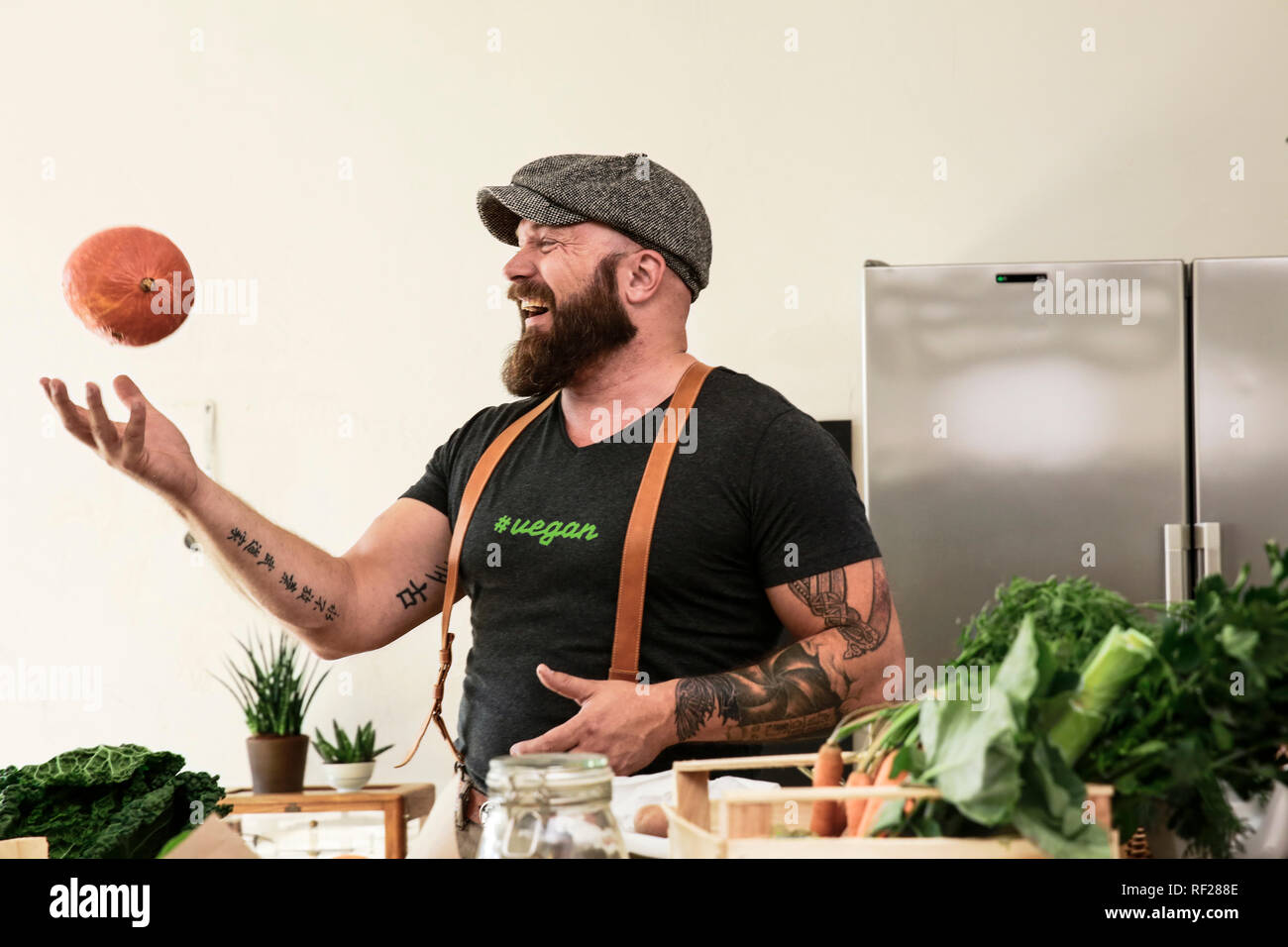 Vegan man playing with a pumpkin in his kitchen Stock Photo - Alamy