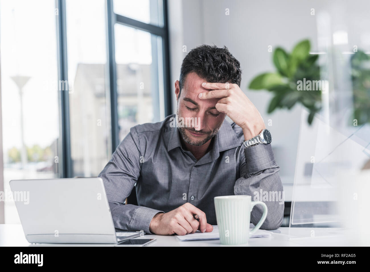 Tired businessman sitting in office Stock Photo - Alamy