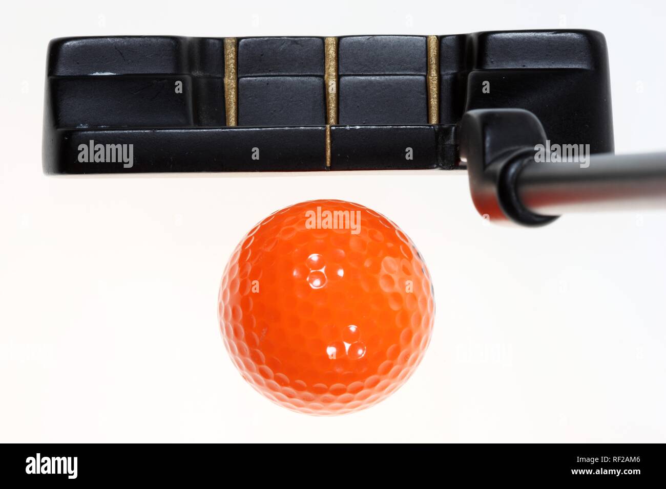 Bright orange golf ball beside head of black putter Stock Photo - Alamy