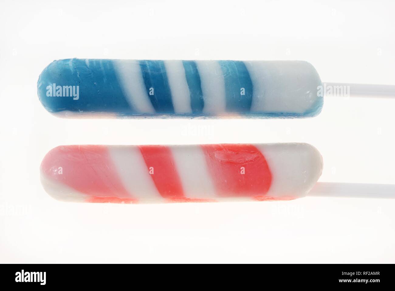 Two hard sugar candy lollipops on sticks, one blue and white striped ...