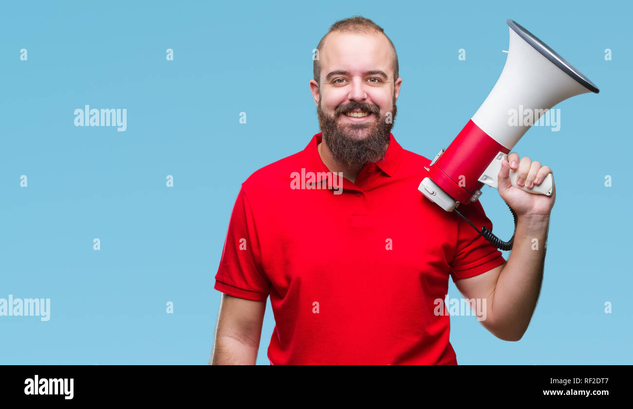Young caucasian man yelling through megaphone over isolated background ...