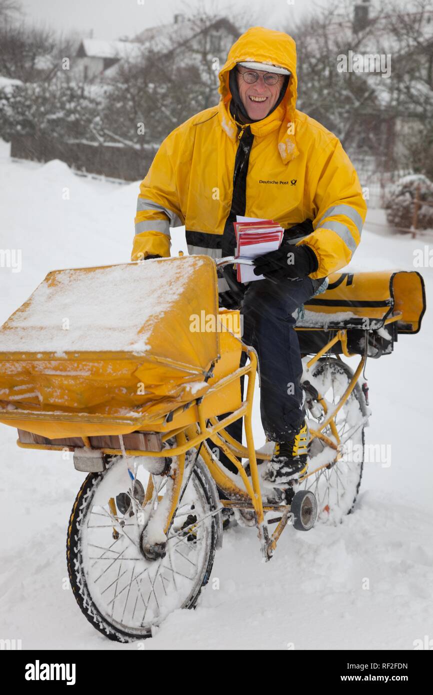 Man, postman, postman on yellow post bicycle in winter conditions ...