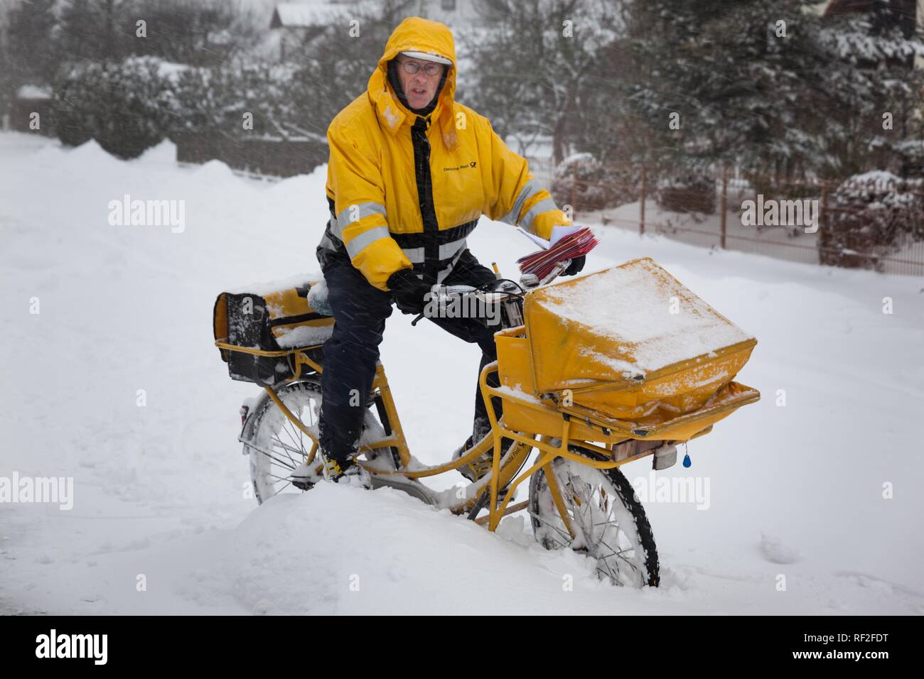 Man, postman, postman on yellow post bicycle in winter conditions ...