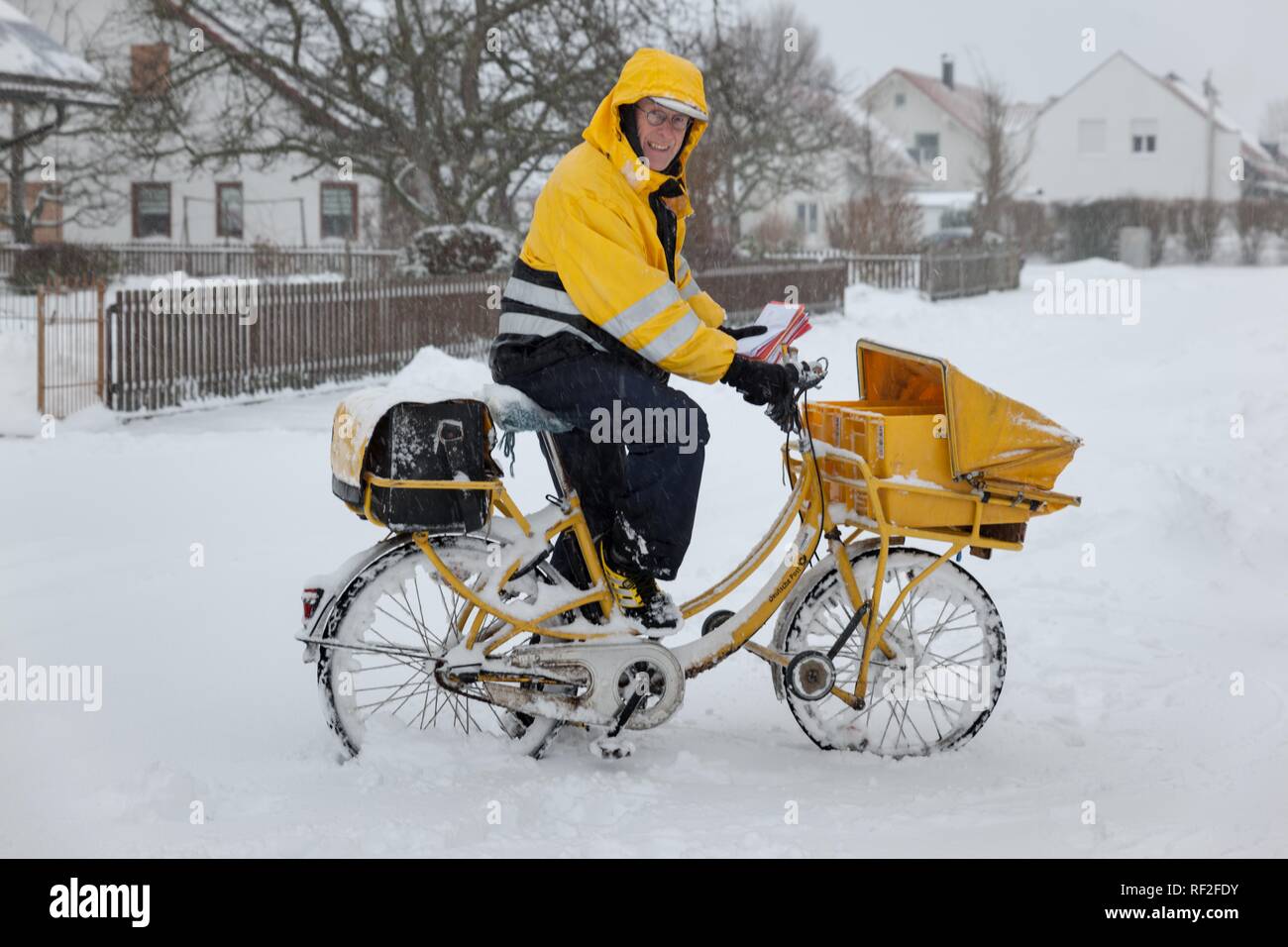 Man, postman, postman on yellow post bicycle in winter conditions ...