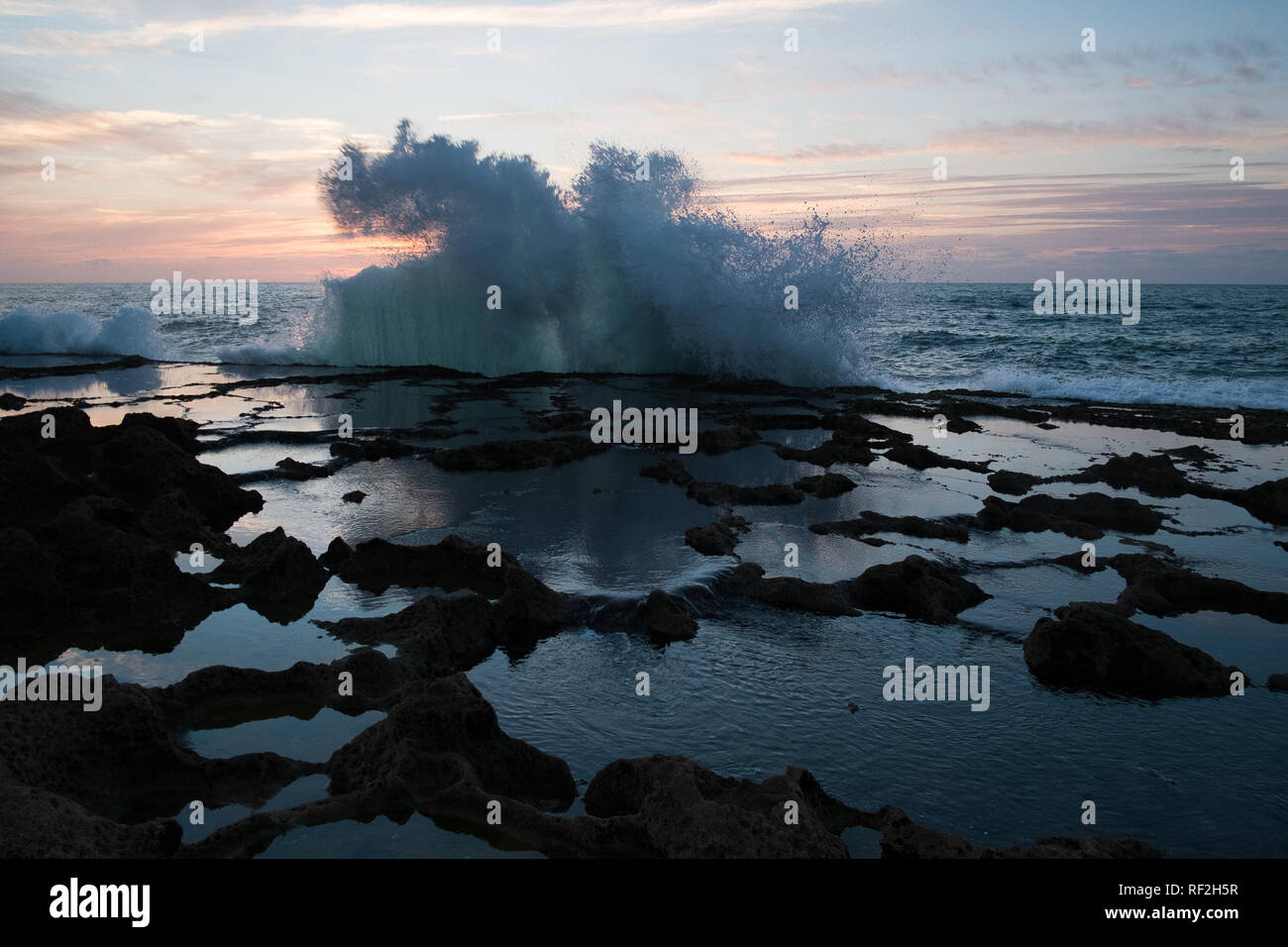 Splash of ocean waves against a background of sunset and rocks Stock ...