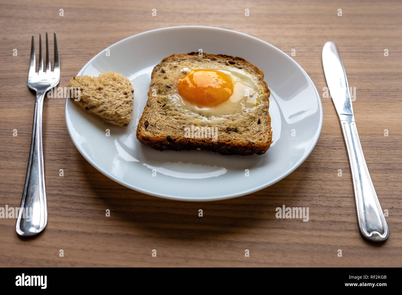 Breakfast concept. White plate with hearts of bread, baked bread and ...
