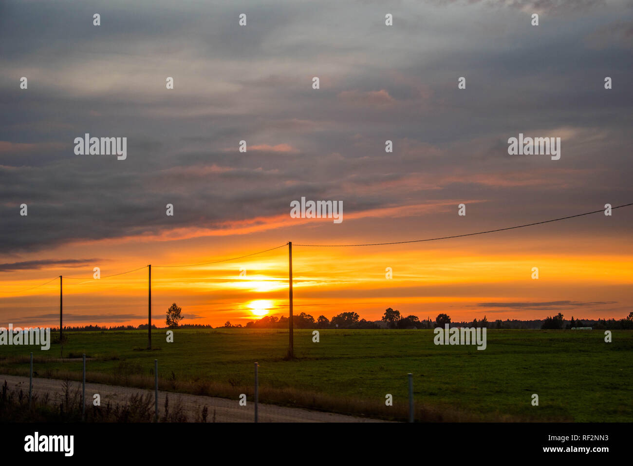 Sunset and dramatic clouds over the green field Stock Photo - Alamy
