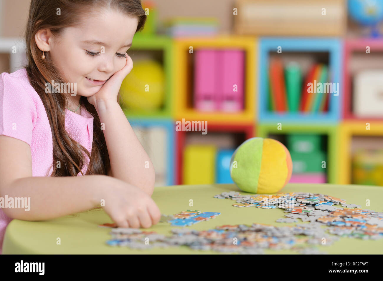 Portrait of cute little girl collecting puzzles Stock Photo - Alamy