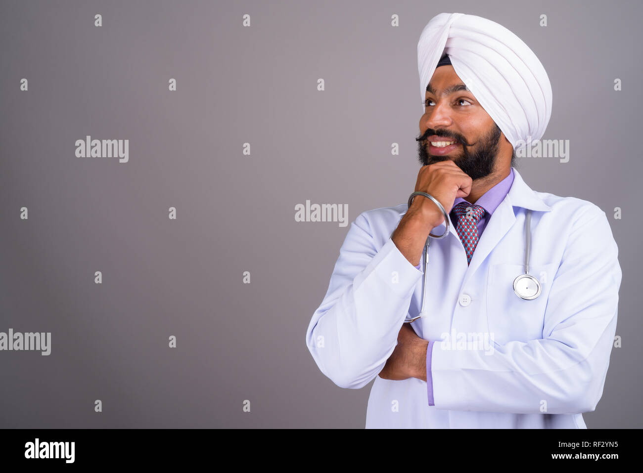 Portrait of young Indian Sikh man doctor smiling and thinking Stock ...