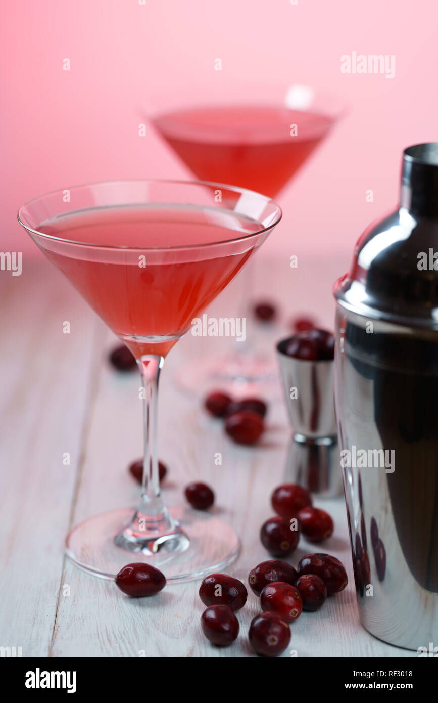 Cosmopolitan cocktail with cranberries, shaker and jigger. White wooden ...
