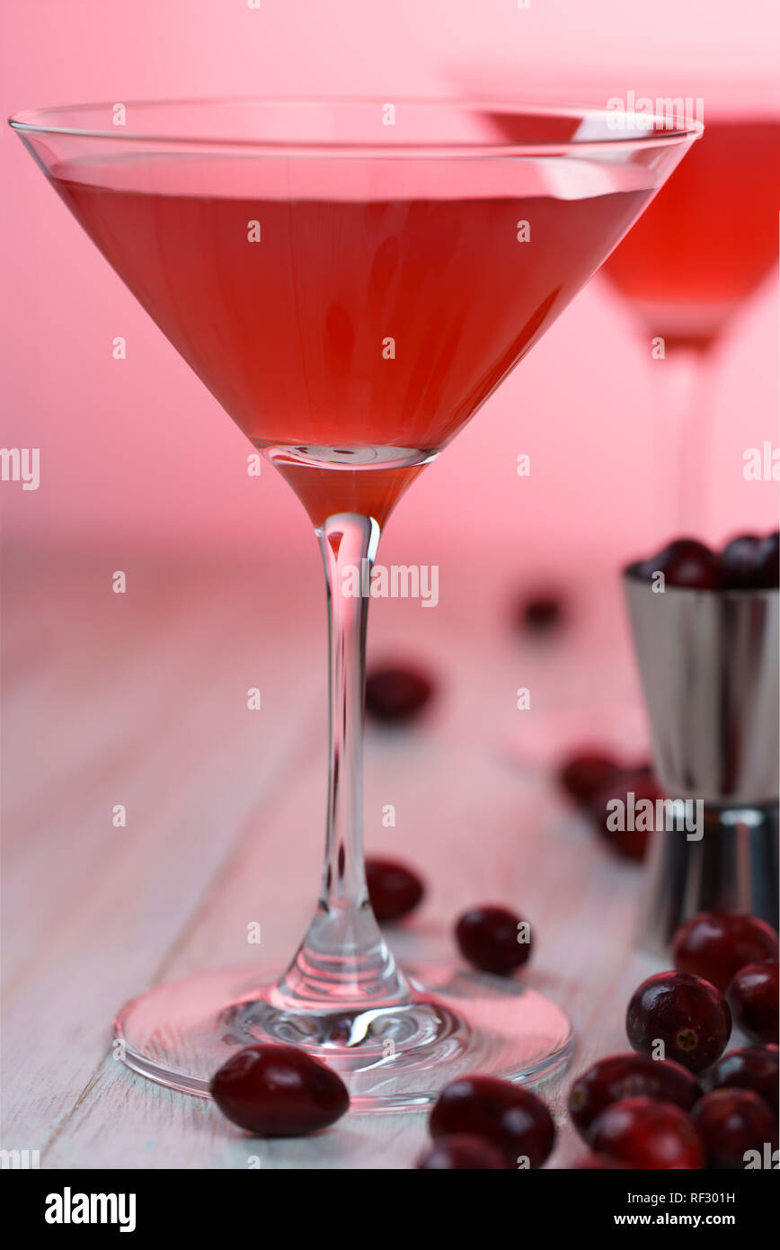 Cosmopolitan cocktail with cranberries, shaker and jigger. White wooden ...