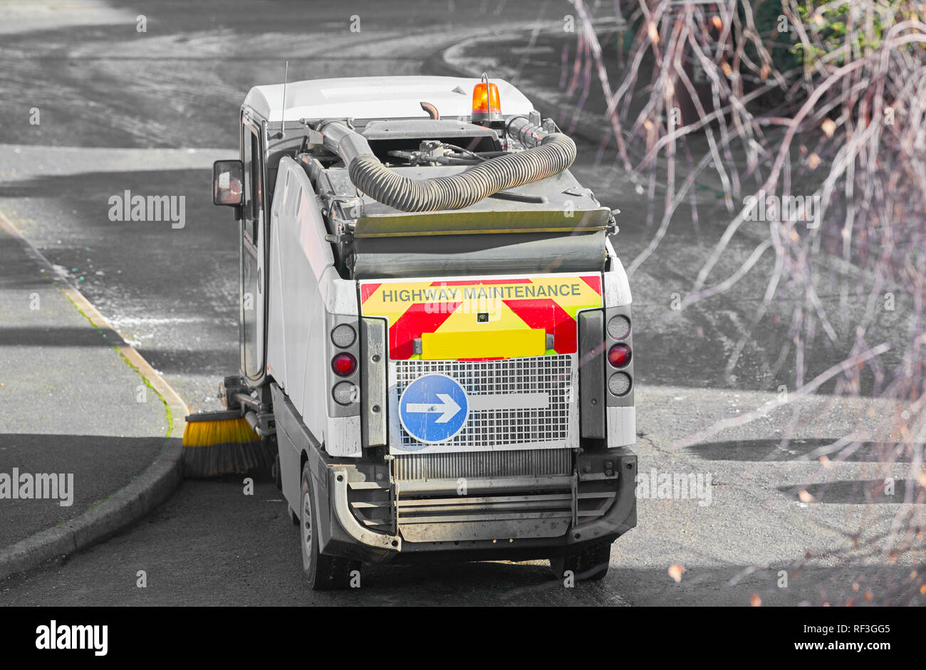 A highway maintenance motorised sweeper drives along a road, with its ...