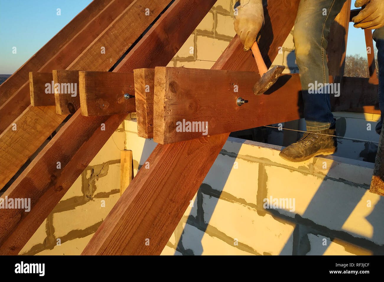 The worker claps the studs with a hammer on the rafters, building a ...