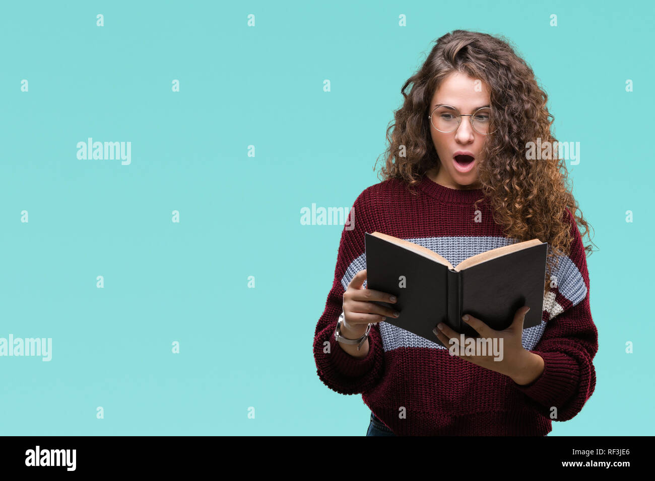 Young brunette girl reading a book wearing glasses over isolated ...