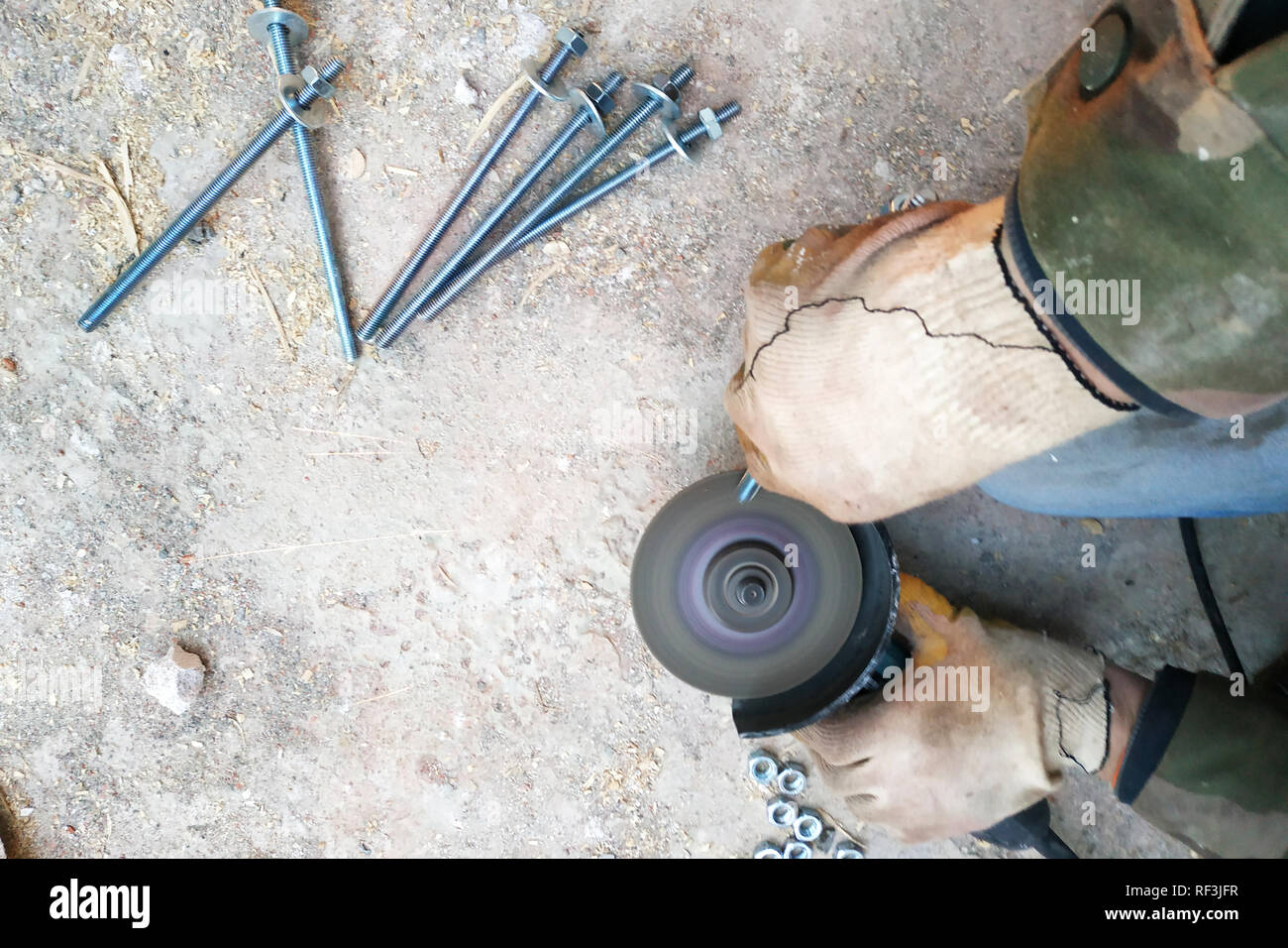 the worker uses an angle grinder to sharpen the bolts, a close-up plan ...