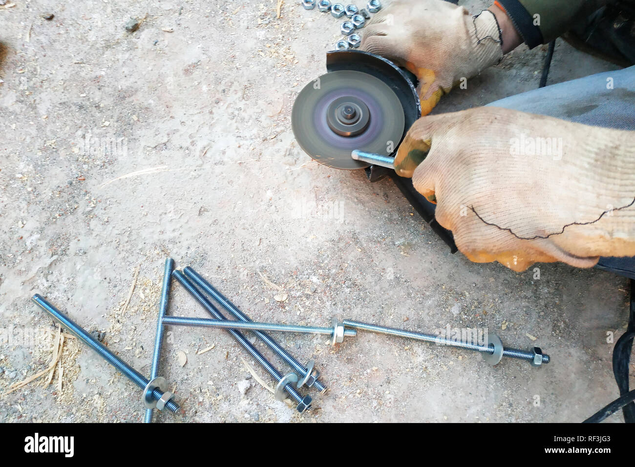 the worker uses an angle grinder to sharpen the bolts, a close-up plan ...